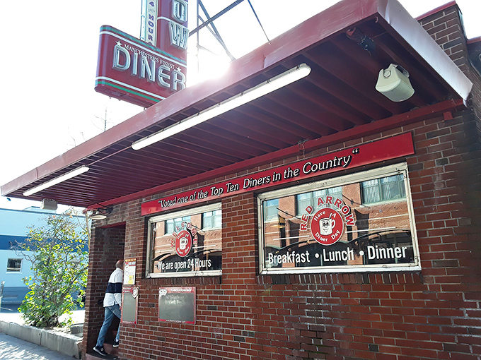 The iconic Red Arrow Diner storefront beckons hungry travelers with its vintage neon sign and promise of 24-hour comfort food. Manchester's brick-and-mortar time machine awaits.