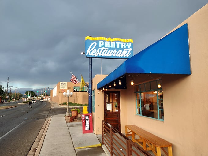 The iconic blue Pantry sign stands like a beacon of breakfast hope against the New Mexico sky, promising culinary salvation to hungry souls below.