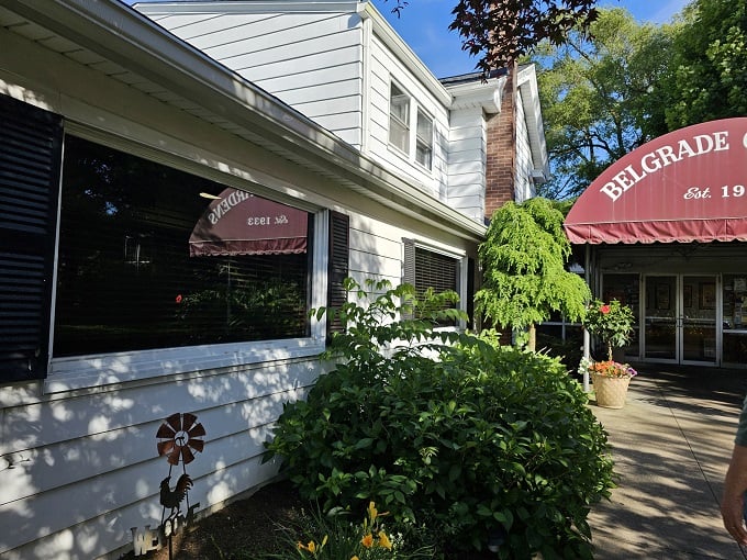 The approach to Belgrade Gardens feels like discovering a secret garden of fried chicken delights, complete with manicured hedges and that iconic burgundy awning.