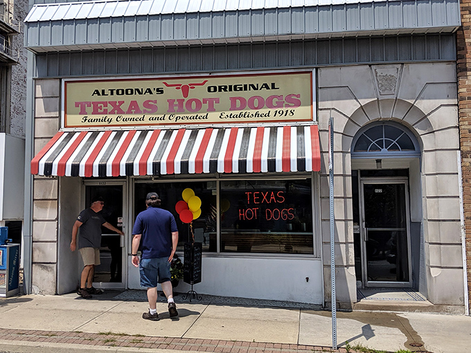The iconic red and white striped awning of Texas Hot Dogs glows like a beacon for hungry travelers. A slice of Americana preserved on Altoona's 12th Avenue.