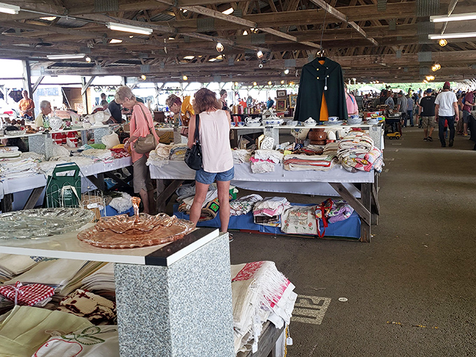 Treasure hunters converge under rustic beams, where plastic bins of potential heirlooms await their next chapter. Every table holds someone else's fond memories.