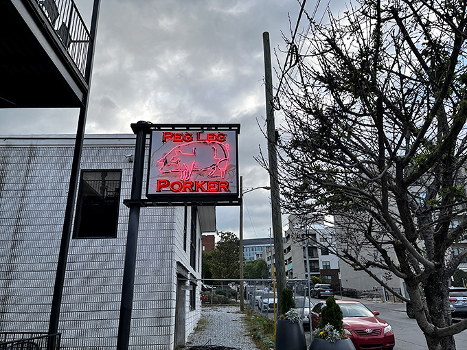 The glowing neon pig sign beckons hungry travelers like a barbecue lighthouse in Nashville's urban landscape.