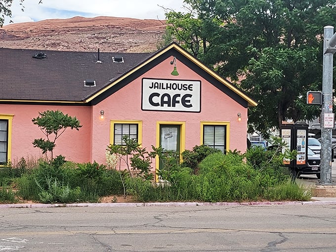 The salmon-pink jailhouse turned breakfast haven stands like a cheerful rebellion against ordinary dining, its yellow door beckoning hungry travelers into delicious captivity.