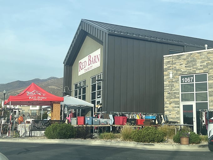 The iconic Red Barn Thrift stands proudly against Utah's mountain backdrop, colorful umbrellas inviting treasure hunters to step inside this Farmington gem.