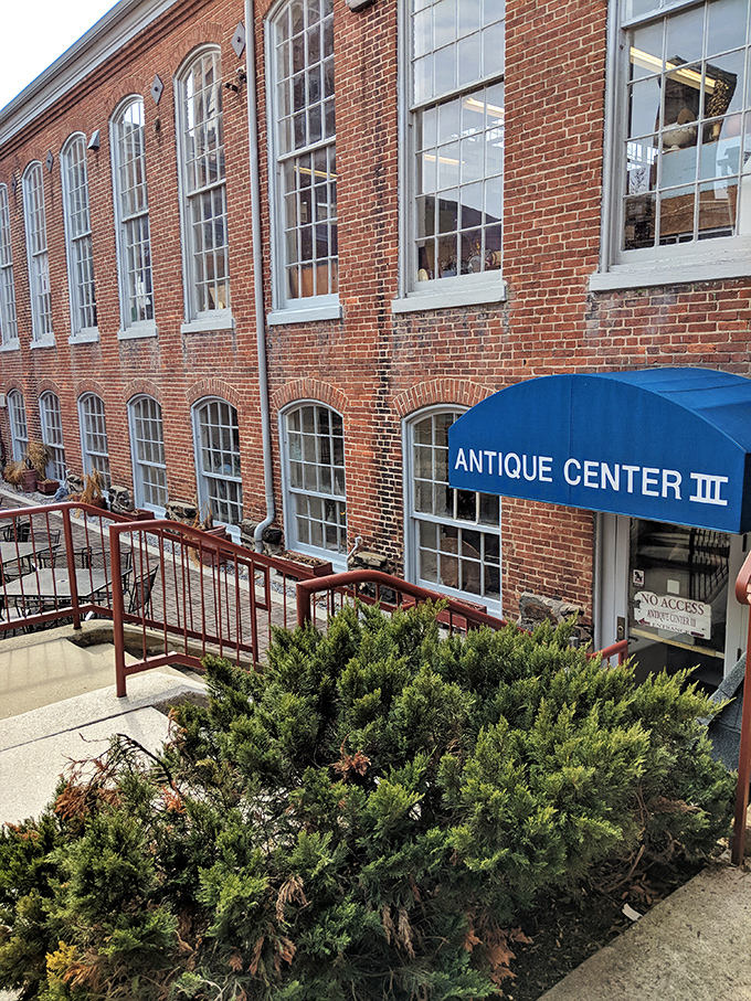The historic brick exterior of Savage Mill welcomes treasure hunters with its distinctive blue awning&mdash;industrial architecture transformed into an antiquing paradise.