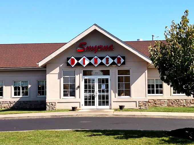 The Smyrna Diner stands proudly against a blue Delaware sky, its cream-colored exterior and distinctive sign promising comfort food salvation to hungry travelers and locals alike.