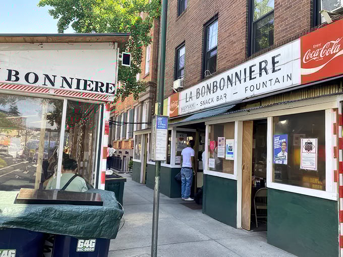 La Bonbonniere's weathered façade stands as a time capsule in the West Village, its vintage sign promising the holy trinity of comfort: burgers, snacks, and fountain treats.