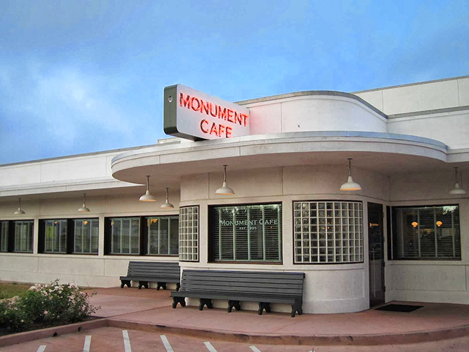 The iconic curved facade of Monument Cafe stands like a mid-century mirage against the Texas sky, promising comfort food paradise within.