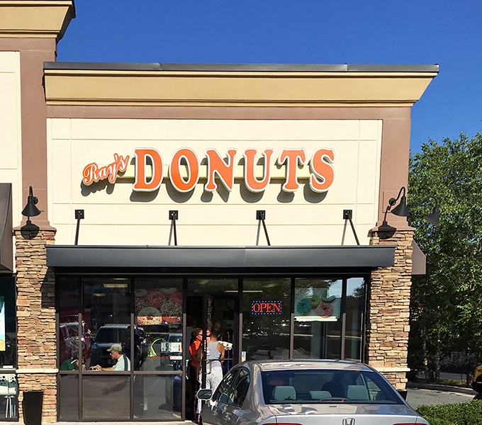 Ray's Donuts announces itself with understated confidence, its stone facade and orange lettering promising sweet treasures within like a suburban Willy Wonka factory.
