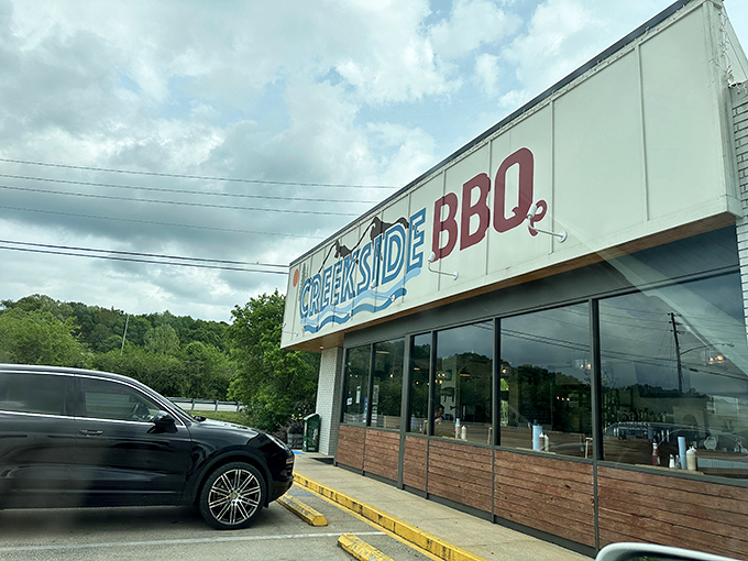 The blue and red Creekside BBQ sign beckons like a lighthouse for the hungry, promising smoky treasures inside this Pelham landmark.