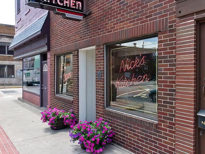 The iconic red neon sign of Nick's Kitchen stands as a beacon of breakfast hope against the brick facade, promising culinary treasures within.