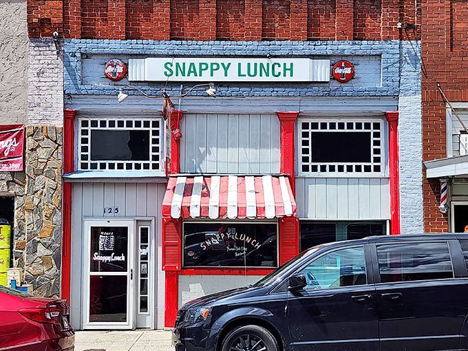 The time-traveling storefront of Snappy Lunch beckons with its cheerful red and blue facade, a nostalgic beacon on Mt. Airy's Main Street since 1923.