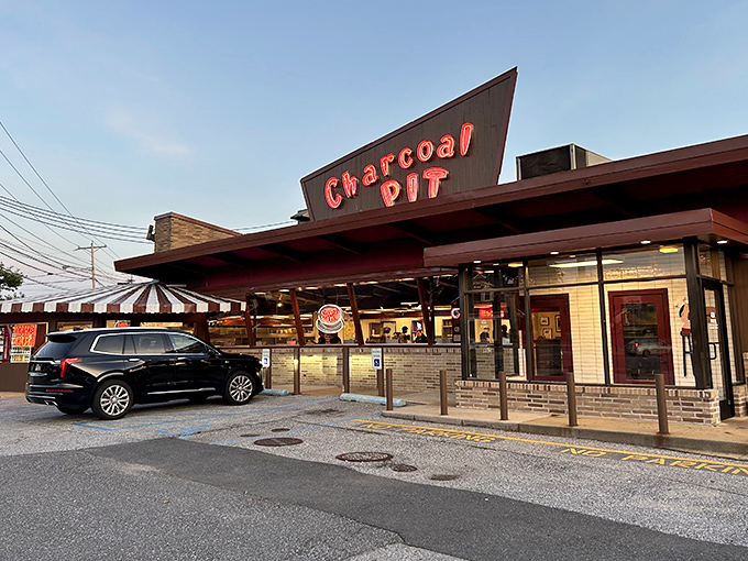 The iconic red neon sign of Charcoal Pit glows like a beacon of burger hope on Concord Pike, promising a time-traveling culinary adventure since 1956.
