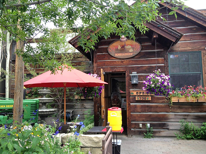 The log cabin exterior of The Kneadery welcomes hungry travelers with rustic charm and hanging flower baskets that say "Yes, breakfast is worth the drive."