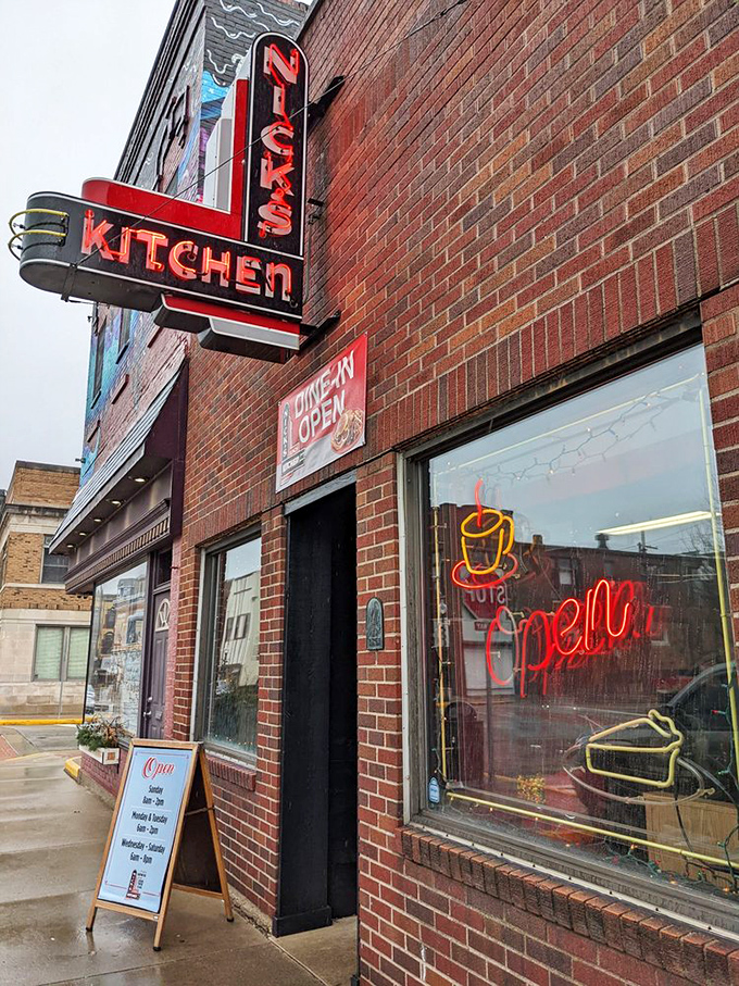 The iconic red neon sign of Nick's Kitchen stands as a beacon of breakfast hope against the brick facade, promising culinary treasures within.