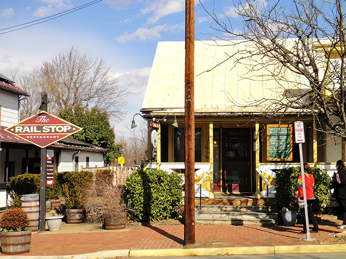 The charming yellow exterior of The Rail Stop beckons like an old friend, promising comfort and culinary delights beside that distinctive red sign.