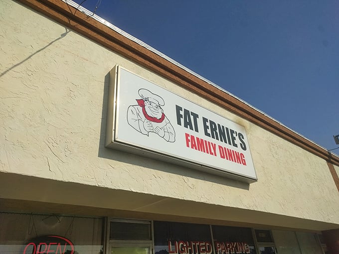 The unassuming exterior of Fat Ernie's Family Dining &ndash; where culinary treasures hide behind beige walls and a cartoon chef who seems to know something you don't.