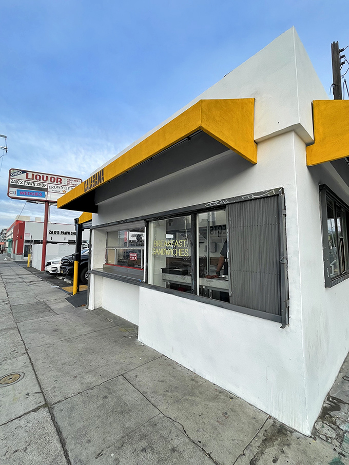 The corner of Santa Monica Boulevard where breakfast dreams come true. That yellow awning is like a culinary lighthouse guiding hungry souls to sandwich salvation.
