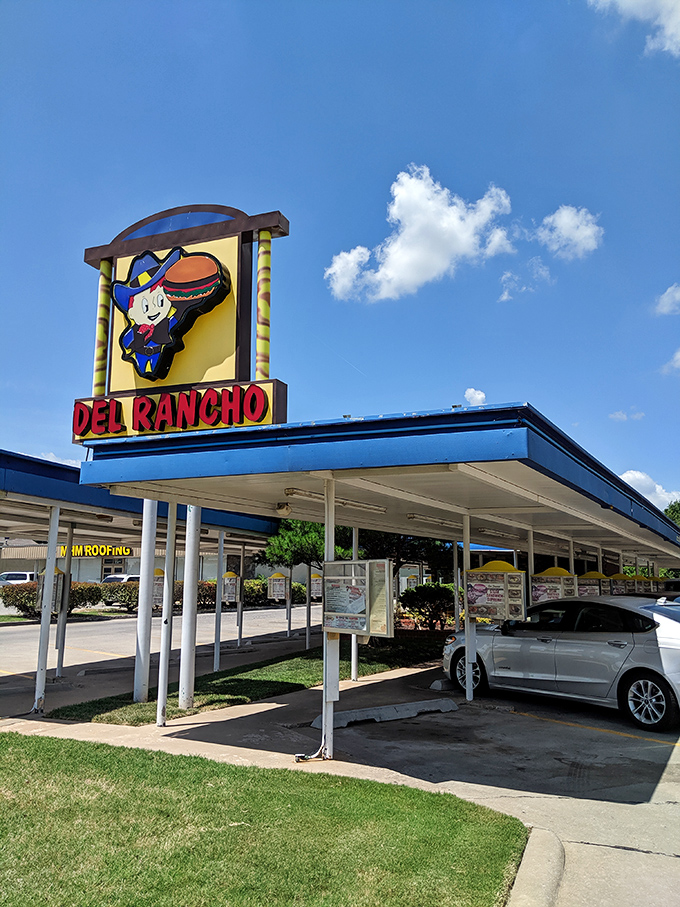 The classic drive-in canopy stands like a time portal to 1956, promising comfort food treasures beneath its nostalgic blue trim. 