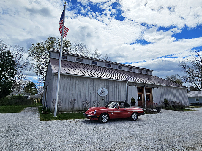 The soaring wooden beams of this converted barn create a cathedral-like space where automotive history comes to life beneath warm, natural light.