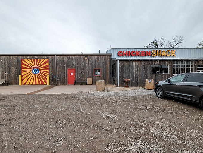 The humble wooden exterior of Chicken Shack stands proudly against an Oklahoma sky, its bold red and yellow sign promising poultry perfection inside.