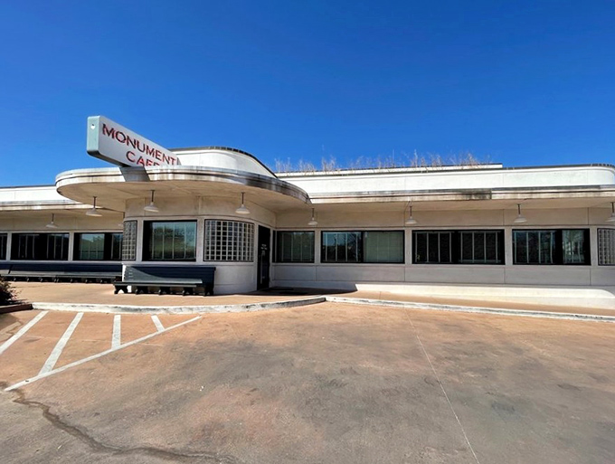 The iconic curved facade of Monument Cafe stands like a mid-century mirage against the Texas sky, promising comfort food paradise within.