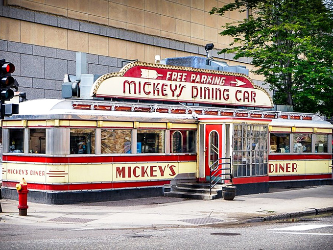 Mickey's iconic red and cream exterior stands like a time capsule on St. Paul's street corner, beckoning hungry travelers with its neon promise of comfort food.