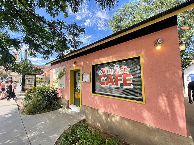 The salmon-pink jailhouse turned breakfast haven stands like a cheerful rebellion against ordinary dining, its yellow door beckoning hungry travelers into delicious captivity.
