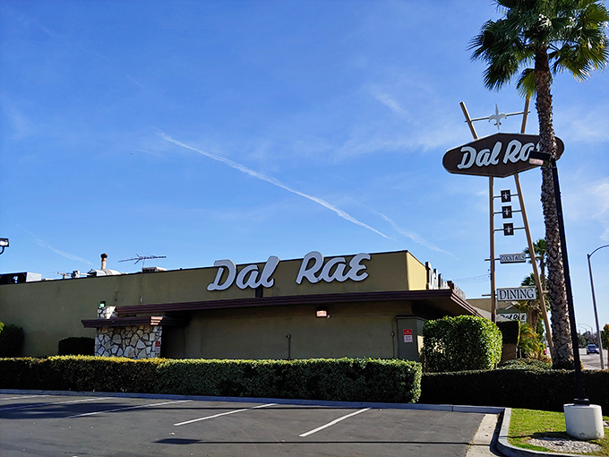 The neon sign beckons like a lighthouse for hungry souls. Palm trees and classic cars complete this quintessential Southern California supper club scene.