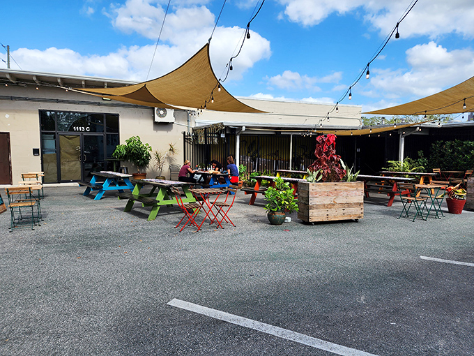 Colorful picnic tables under tan shade sails create an inviting oasis where carb-lovers gather like pilgrims at a delicious shrine.