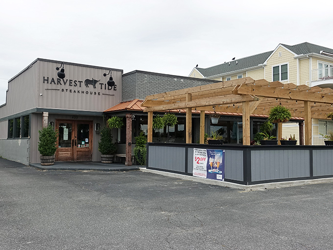 The coastal charm of Harvest Tide Steakhouse beckons from its light-colored exterior, where wooden doors promise carnivorous delights within.