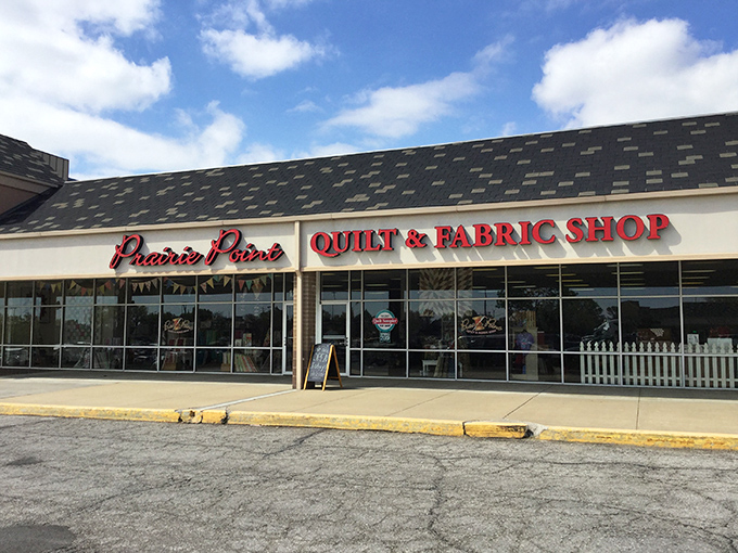 The quilter's equivalent of Willy Wonka's factory beckons with its bright red signage, promising fabric treasures behind those unassuming storefront windows.