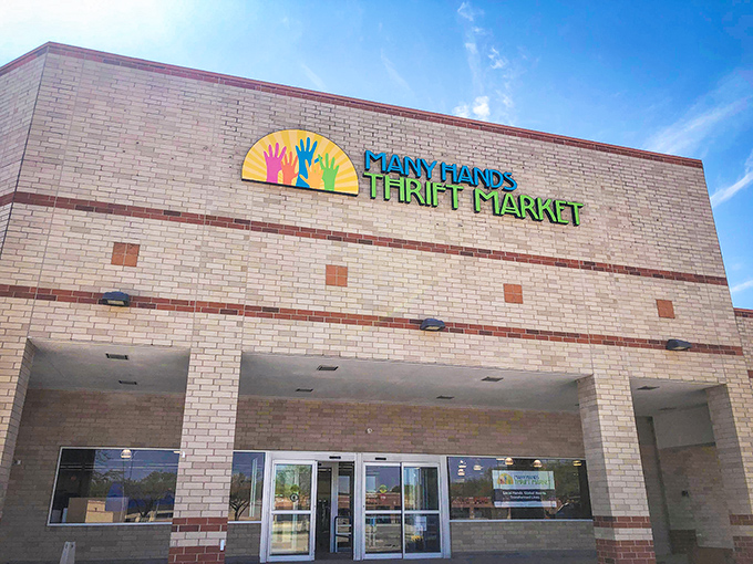 The bright yellow logo featuring colorful hands reaching skyward welcomes bargain hunters like a thrifting bat signal against Clive's clear blue skies.