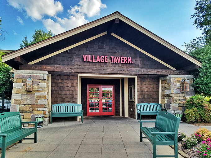 The rustic stone fa&ccedil;ade and welcoming teal benches at Village Tavern's entrance promise comfort before you even cross the threshold. 