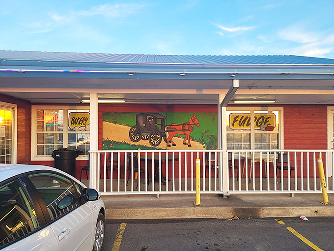 The welcoming front porch of Amish Country Store beckons with its classic red siding, white railings, and that charming "Amish Buggy Xing" sign that promises authentic flavors await inside. 