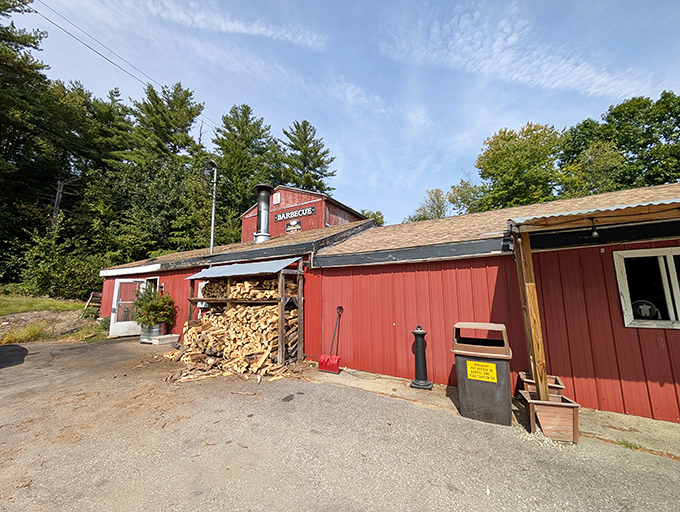 The weathered red barn exterior isn't just rustic charm—it's a smoke signal to BBQ pilgrims that authentic flavor awaits inside this New Hampshire treasure.