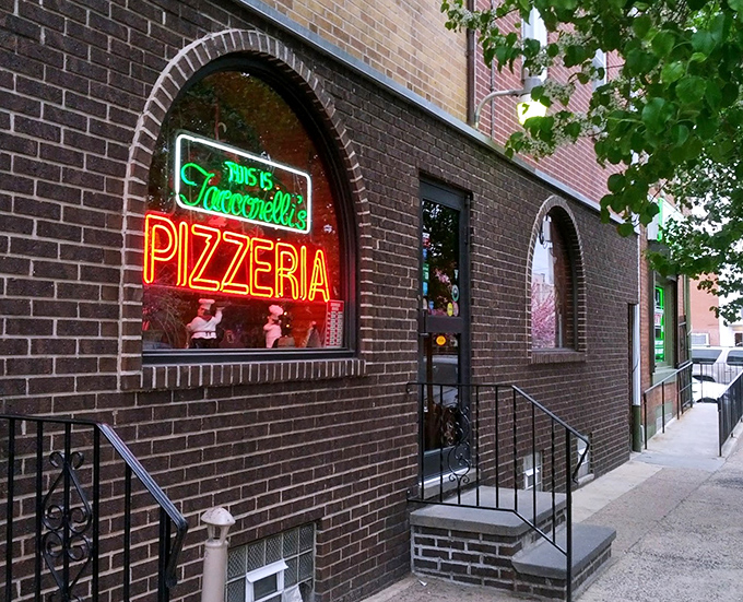 The neon glow of Tacconelli's sign beckons pizza pilgrims like a lighthouse for the carb-obsessed. Pizza paradise awaits behind that brick facade.