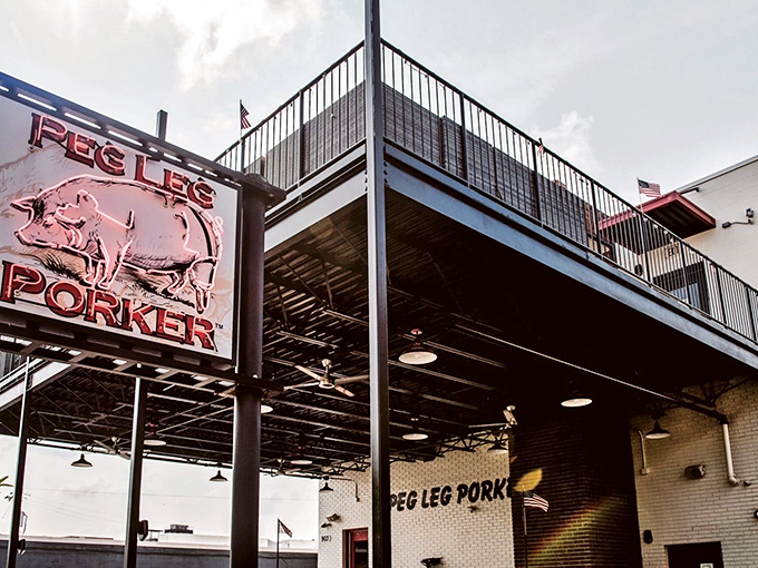 The glowing neon pig sign beckons hungry travelers like a barbecue lighthouse in Nashville's urban landscape.