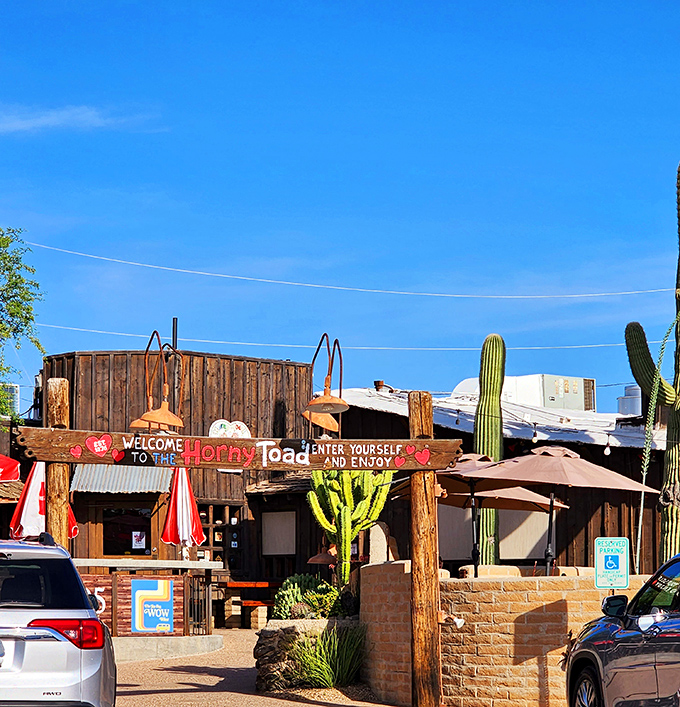The Horny Toad's weathered wooden exterior stands like a time capsule of the Wild West, complete with saguaro sentinels guarding desert-worn pathways. 