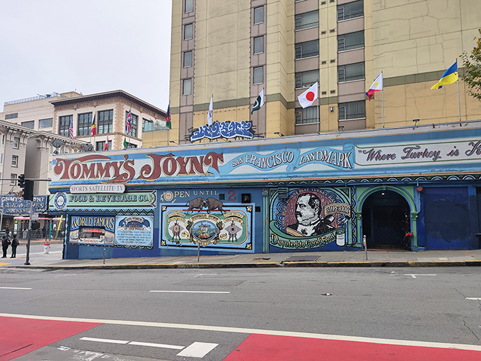 The unmistakable blue exterior of Tommy's Joynt stands like a colorful time capsule on Van Ness Avenue, complete with international flags and hand-painted promises of culinary delights within.