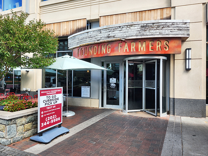 The welcoming entrance to MoCo's Founding Farmers beckons with its distinctive curved awning and warm wooden accents. Farm-to-table paradise awaits!