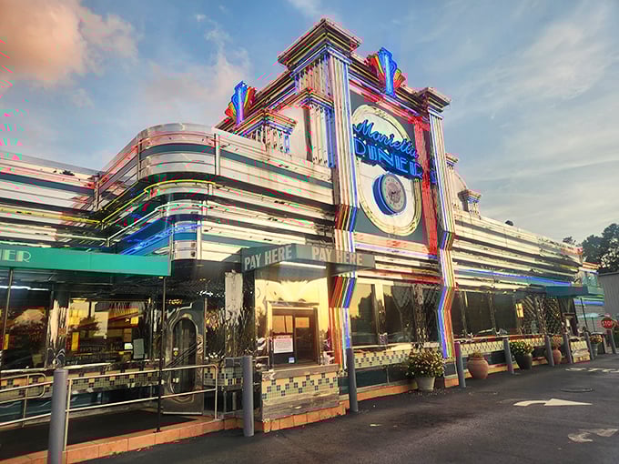 The neon-drenched facade of Marietta Diner glows like a beacon for hungry souls, a chrome-clad time machine promising comfort food and nostalgia.