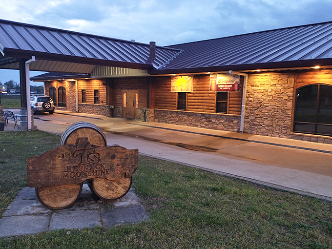 The log cabin exterior of T's Redneck Steakhouse glows with warm invitation as dusk settles, promising carnivorous delights within those rustic walls.