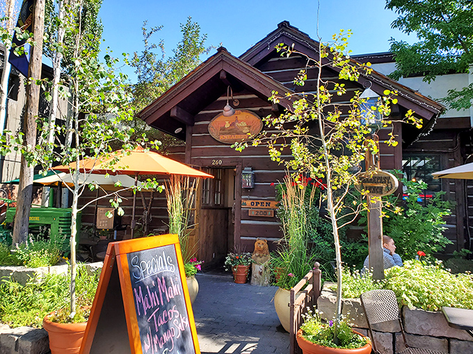 The log cabin exterior of The Kneadery welcomes hungry travelers with rustic charm and hanging flower baskets that say "Yes, breakfast is worth the drive."
