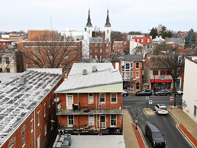 Frederick's twin spires pierce the sky like exclamation points, announcing "History lives here!" amid a sea of brick buildings and modern life.