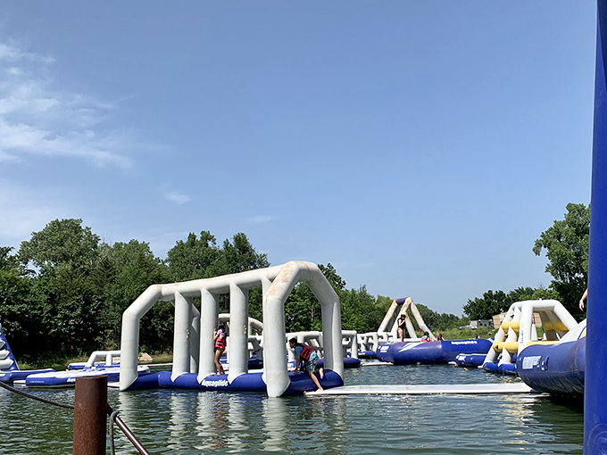 The ultimate adult playground where dignity takes a vacation. White inflatable obstacles float invitingly on blue water, promising equal parts joy and inevitable splashing.