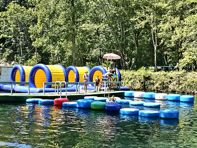 Where the magic happens! Colorful inflatable obstacles float invitingly on crystal-clear quarry waters, promising adventures that'll make your inner child high-five your actual children.
