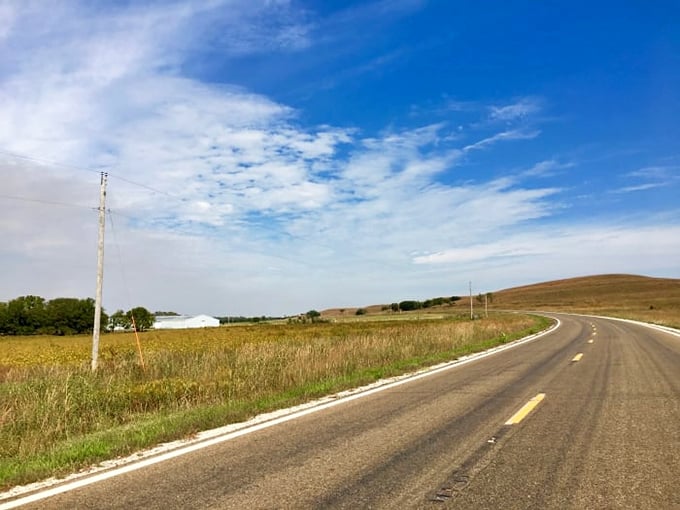 The road stretches toward infinity, where Kansas sky meets prairie in a perfect horizon. This is freedom defined.