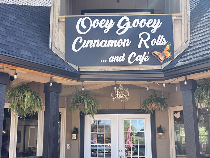 The charming cottage-style exterior of OoeyGooey beckons with bright red umbrellas and rustic wooden tables, promising sweet treasures within.