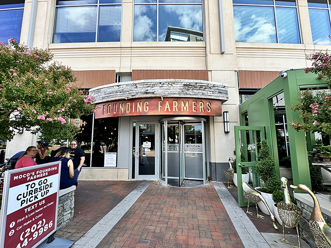 The welcoming entrance to MoCo's Founding Farmers beckons with its distinctive curved awning and warm wooden accents. Farm-to-table paradise awaits!